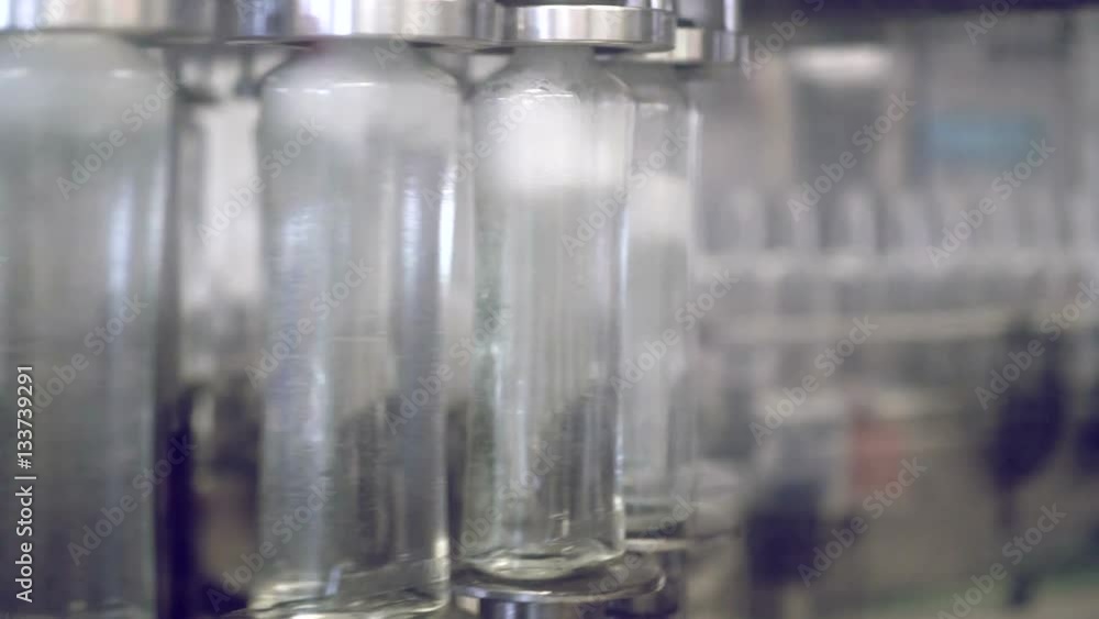 Spill of alcohol in glass bottles at the plant. Conveyor belt with ...