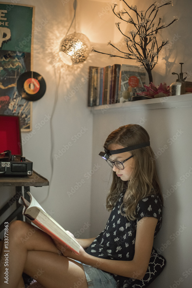 Girl reading book in quiet corner using head torch Stock Photo | Adobe ...