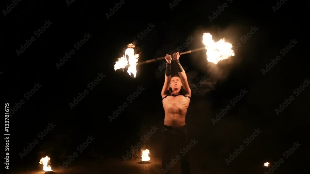 Fire show. Handsome male fire performer twirling fire baton with ...