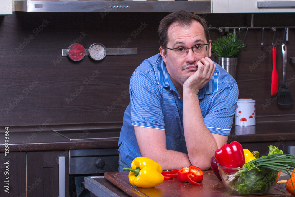 Portrait of adult sad man cooking in the kitchen Stock Photo | Adobe Stock
