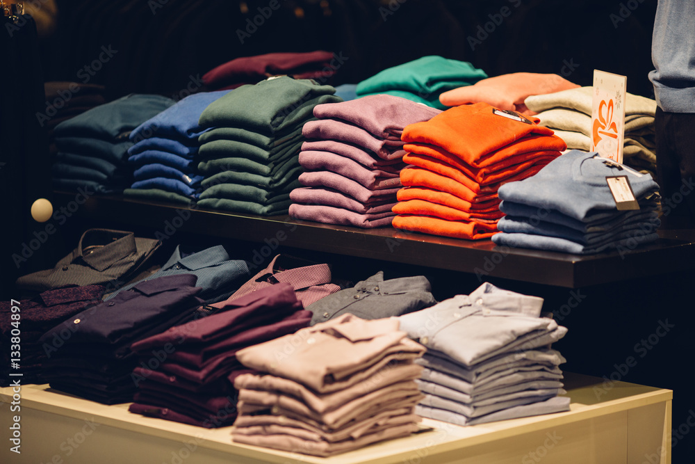 Clothing store in shopping mall. Stack of folded colorful clothes in a ...