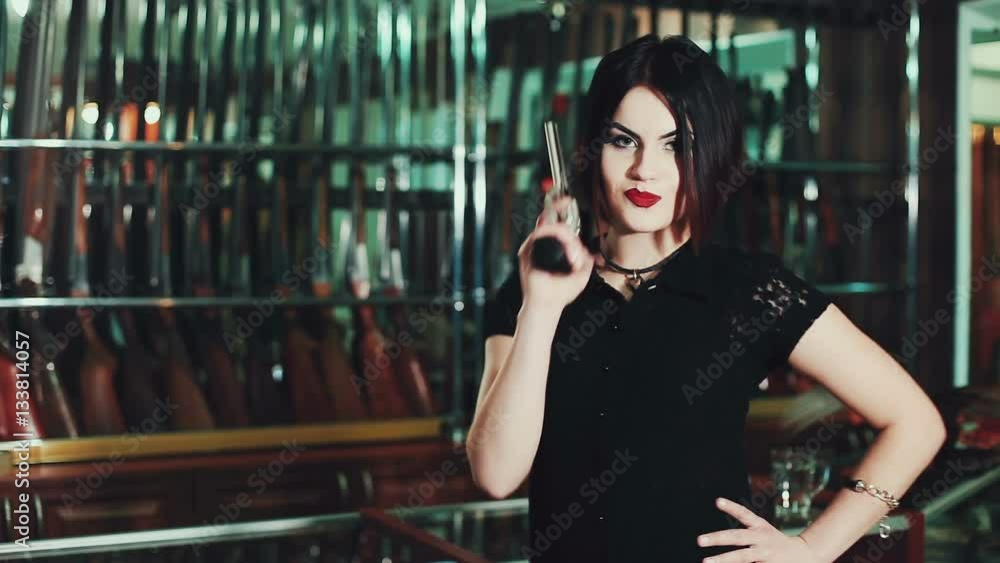 The girl with dark hair and red lips, holding a gun in his hand ...