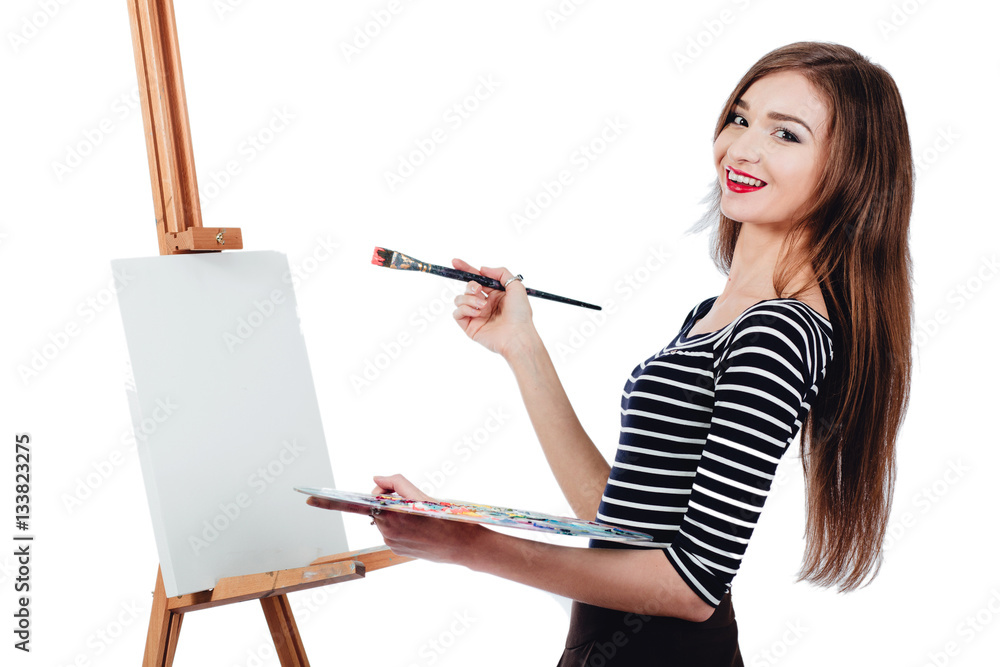 Cute beautiful girl artist painting a picture on canvas easel. Space ...