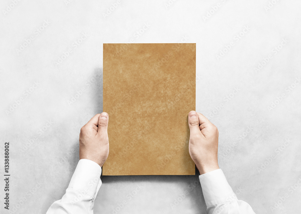Hand holding kraft blank paper sheet mockup, isolated. Arm in shirt ...