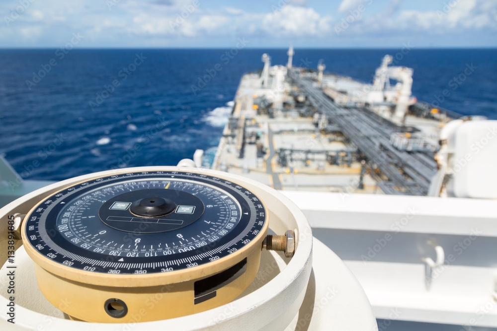 Foto Stock Compass aboard large ship on a blue summer sea. | Adobe Stock