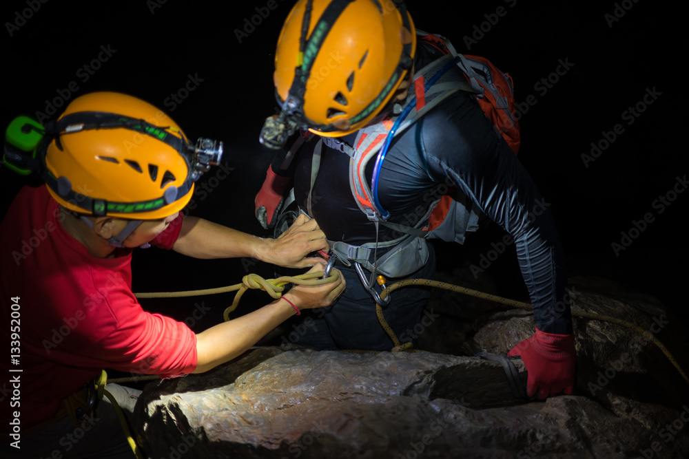 Explorers help each others to tighten climbing equipments with rope ...