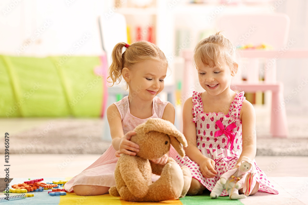 Cheerful little girls playing on floor Stock Photo | Adobe Stock