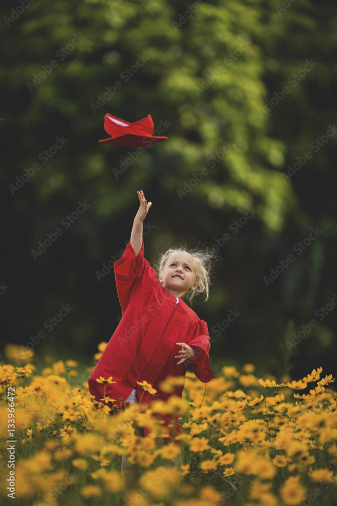 Girl wearing graduation gown throwing cap standing amidst yellow ...