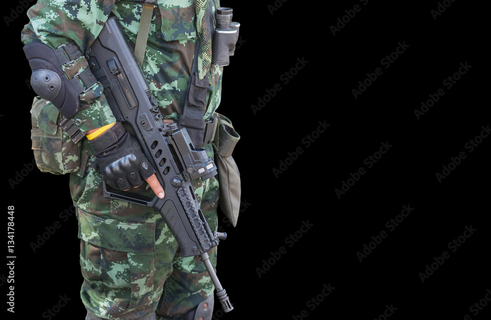 soldier in uniform holding automatic assault rifle on black background ...