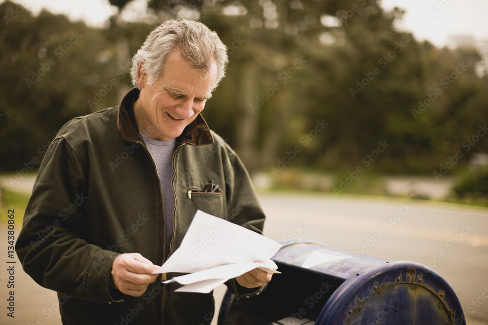 Man standing next to post box reading letter Stock Photo | Adobe Stock