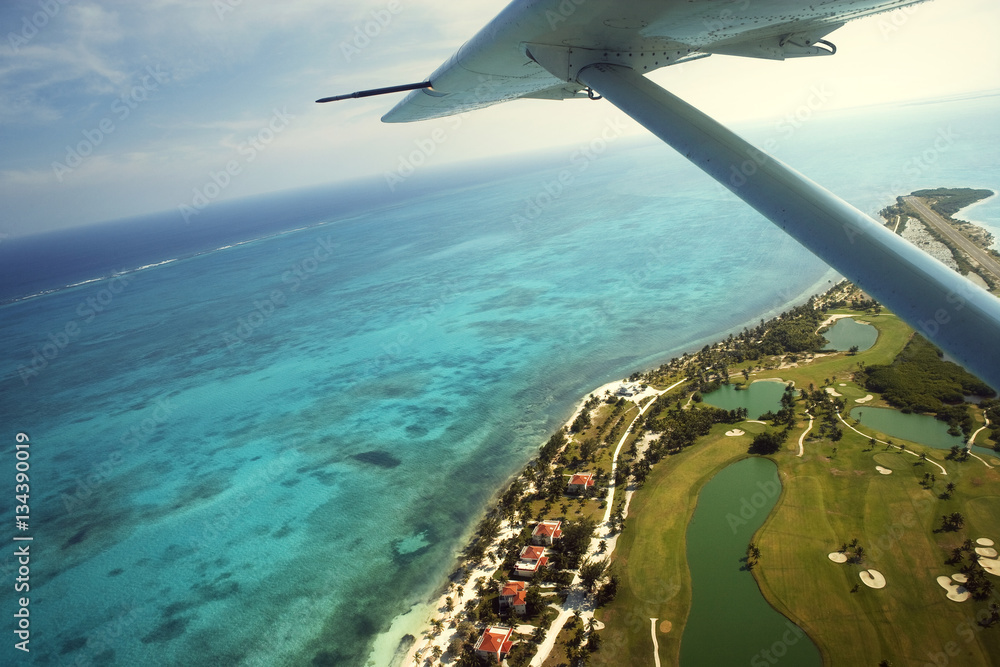 Plane flying over a tropical island. Stock Photo | Adobe Stock