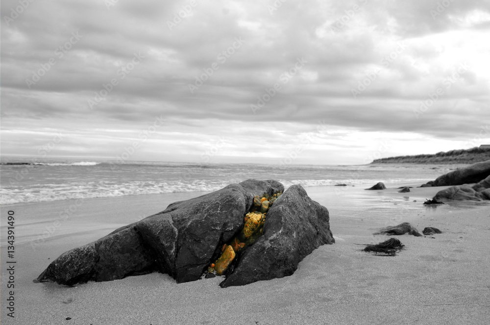 Split boulder on beach with smaller rocks filling up the crack, black ...