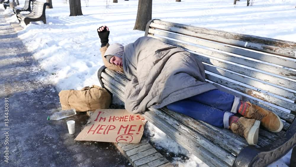 4K. Homeless man sleeping on bench in winter park. Slider shot Stock ...