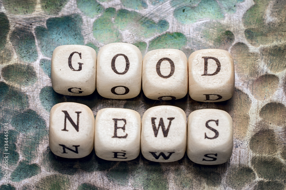 the word good news, lined with wooden blocks on a metal forged textural ...