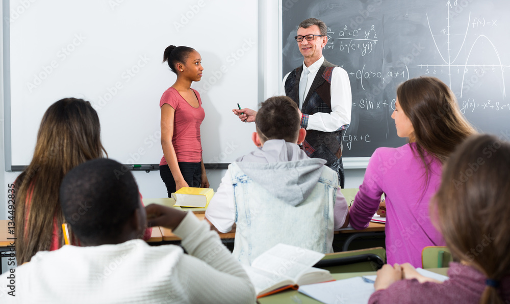 Teacher explaining the math near chalkboard . Stock-Foto | Adobe Stock