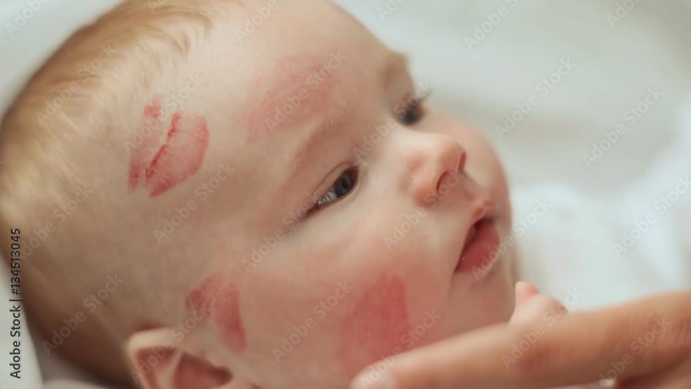Mom erases traces of the kiss on the baby's cheek. The child smiles and ...