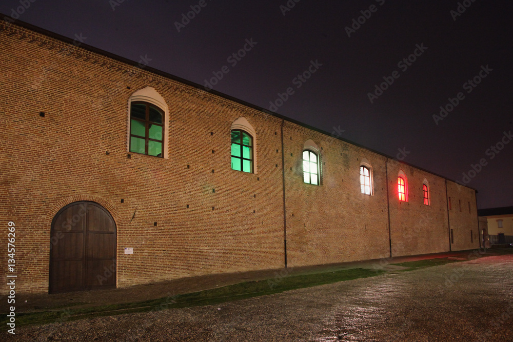 Italian brick public building with wooden door and high windows lit in ...