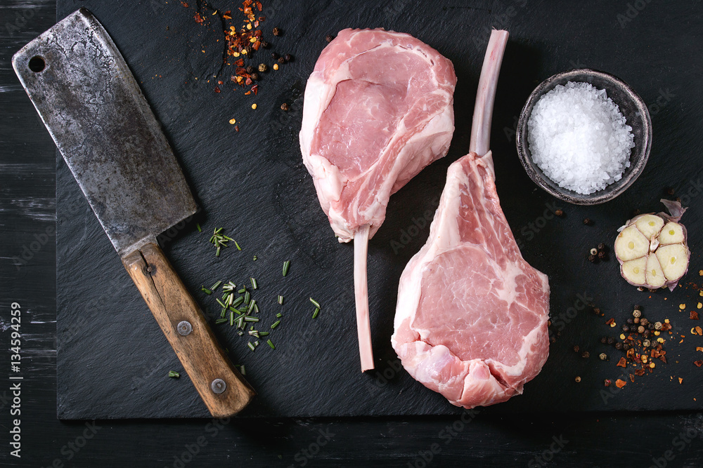 Two raw uncooked Veal tomahawk steak with garlic, salt, seasoning and ...