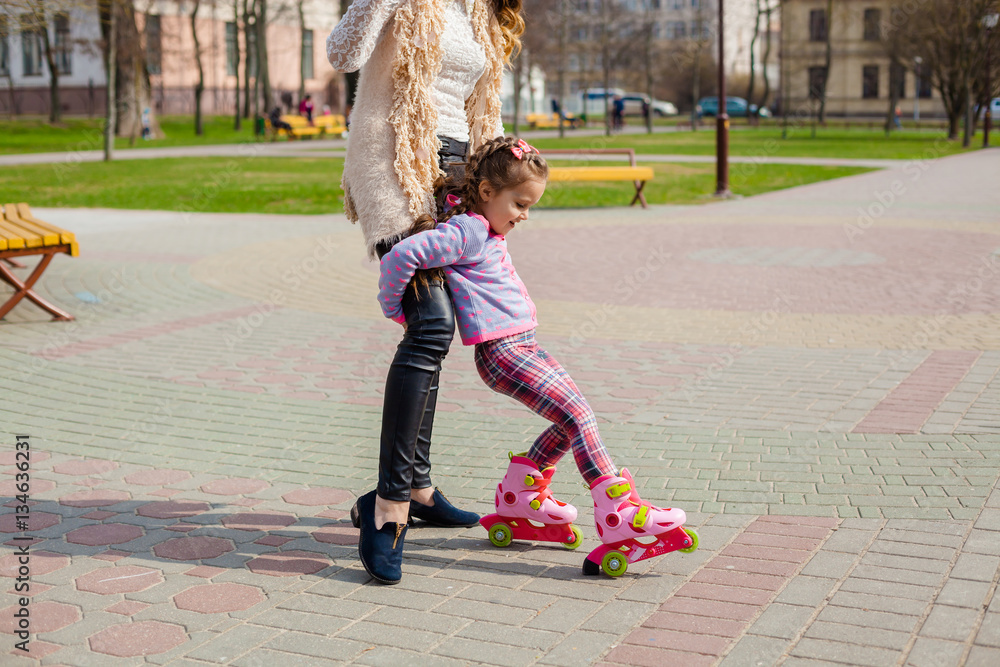 Mom and daughter ride on roller skates. Girl learning to roller skate ...