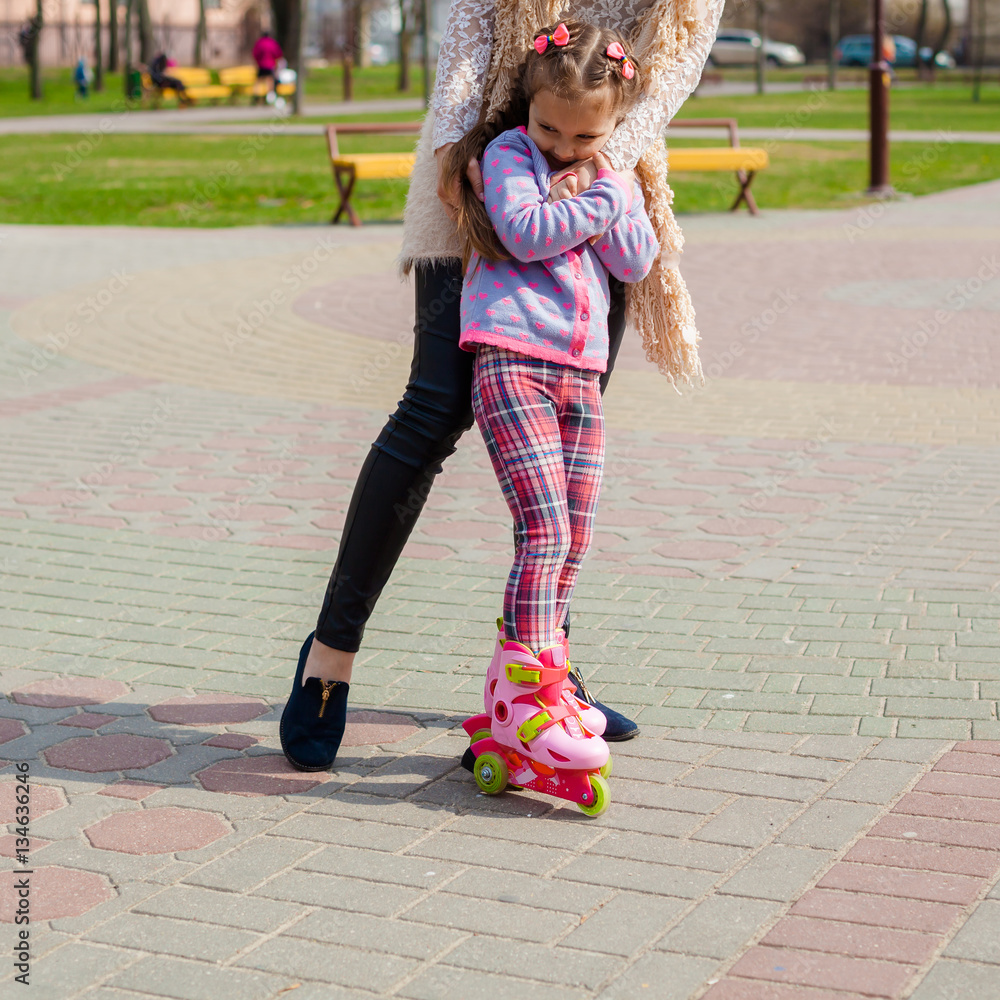 Mom and daughter ride on roller skates. Girl learning to roller skate ...