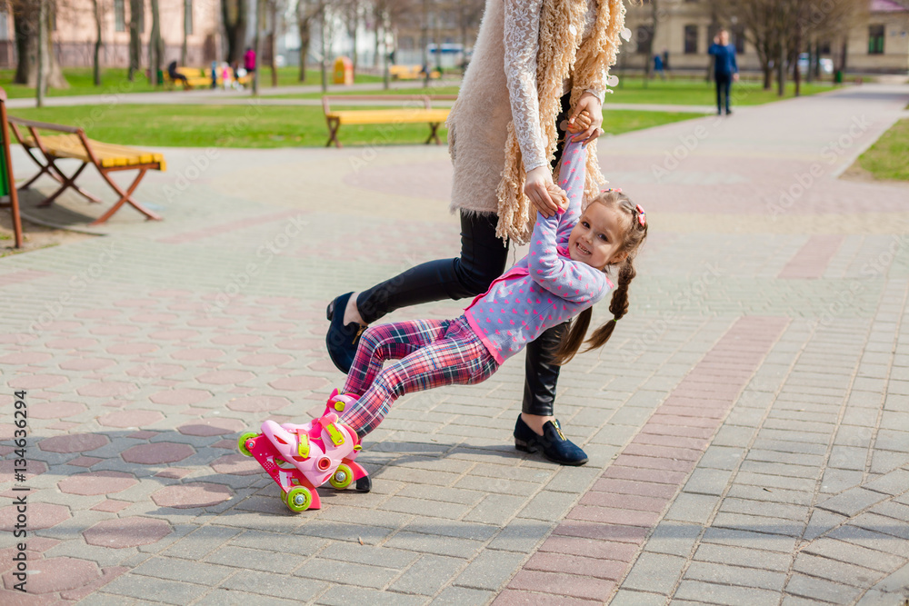 Mom and daughter ride on roller skates. Girl learning to roller skate ...