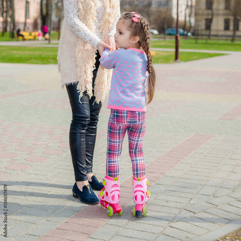 Mom and daughter ride on roller skates. Girl learning to roller skate ...