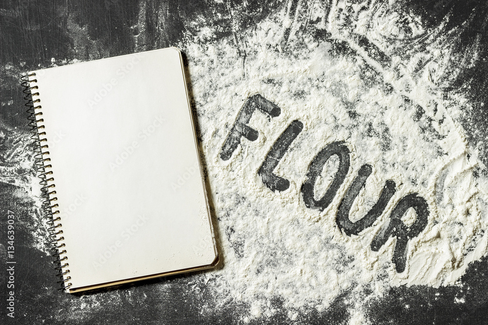 flour on the black background with empty blank notepad. Mockup. Top ...