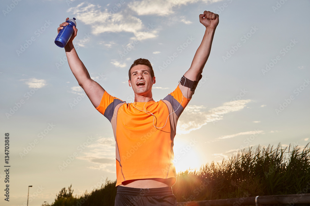 Successful man raising arms after cross country running on summer at ...