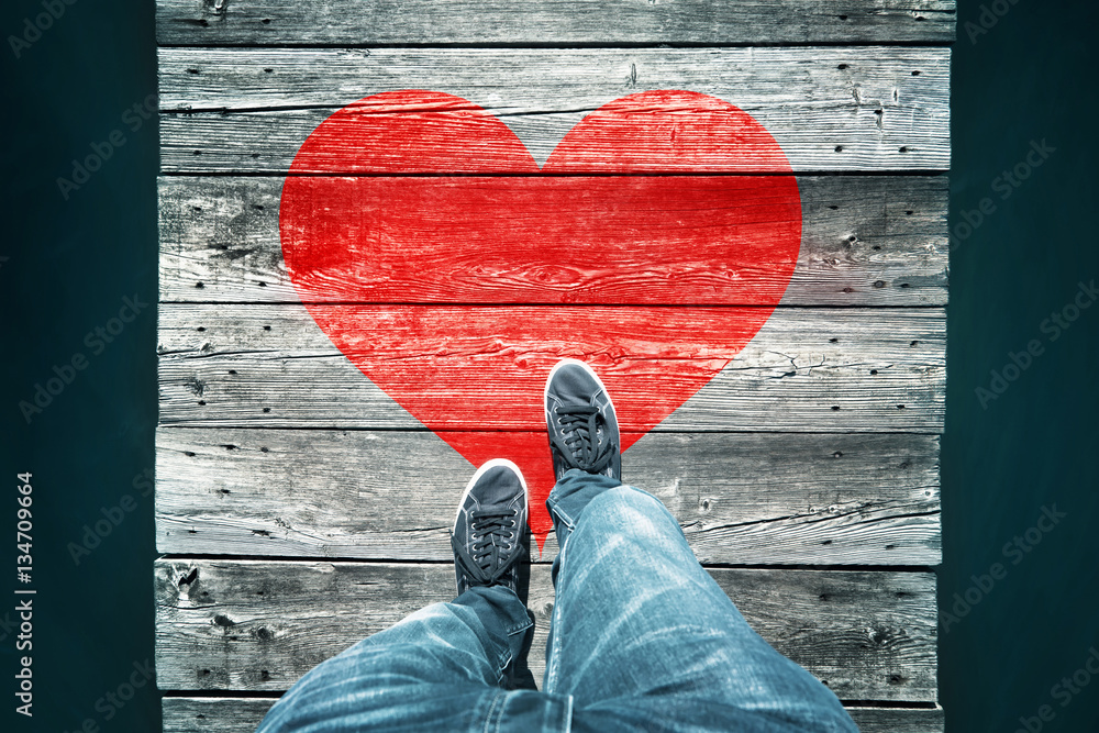 Man walking and crossing aged narrow wooden bridge with painted red ...