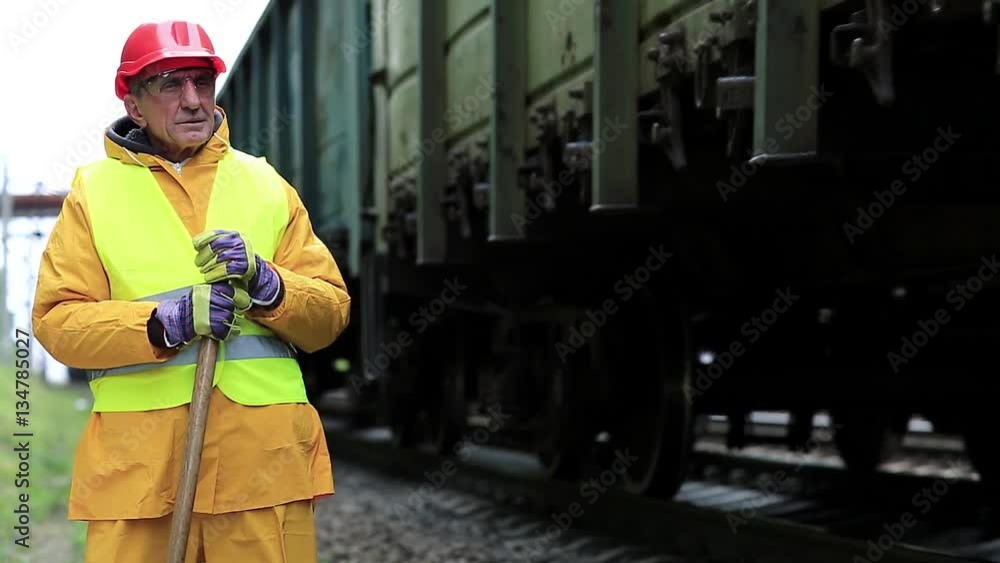 Railway worker looks at passing train. Railway worker in yellow uniform ...