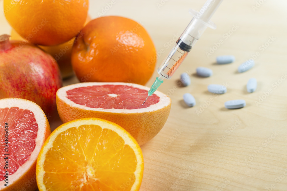 Needle and syringe injected in the fruit. Nutrition concept. Enhanced ...