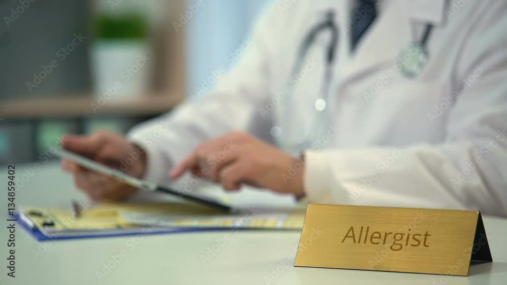 Allergist in white uniform viewing medical documentation on tablet in ...