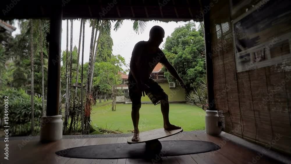 Island of Bali. The young guy trains on specially balance board. The ...