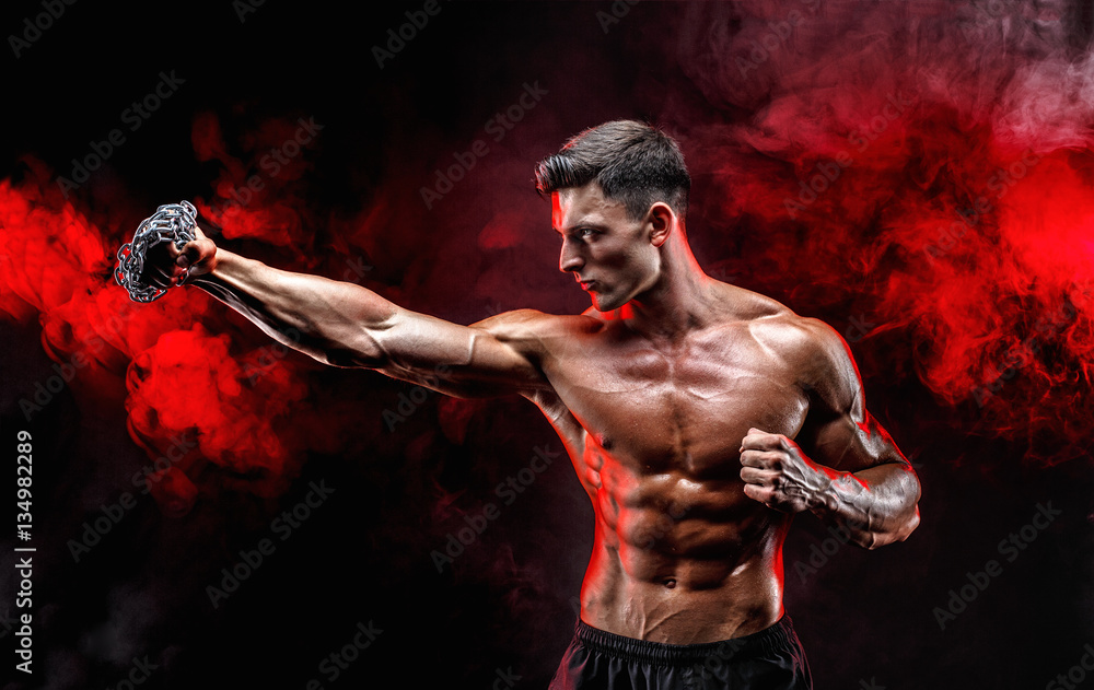Serious muscular fighter doing the punch with the chains braided over ...