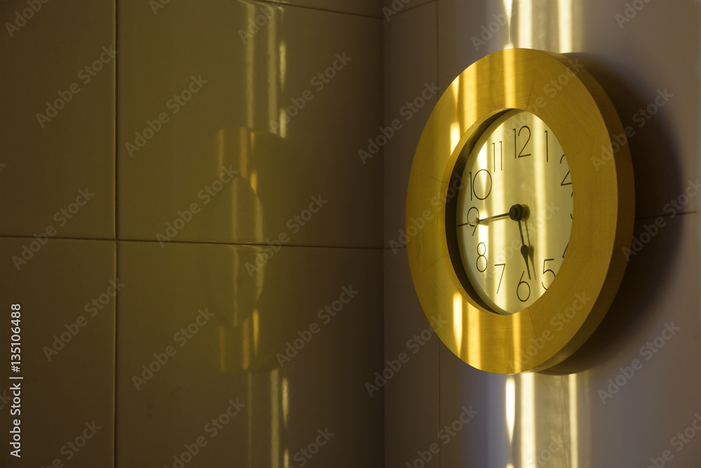 Yellow clock on a wall and some natural light through the window. Empty ...