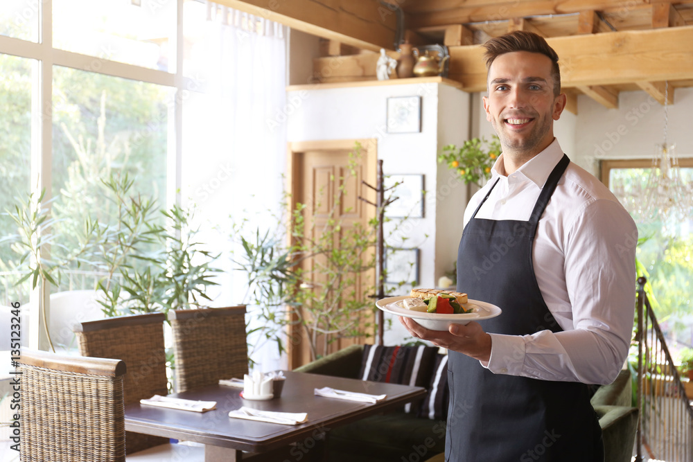 Handsome young waiter serving meals at restaurant Stock-Foto | Adobe Stock