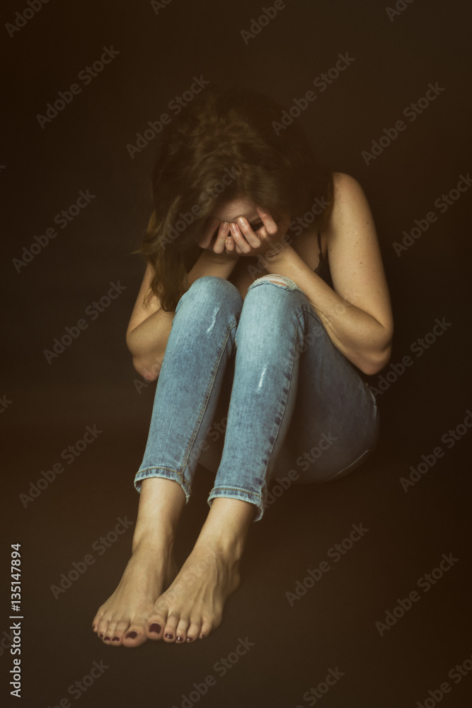 Crying shy girl sitting on the ground. Curled up woman with face in ...