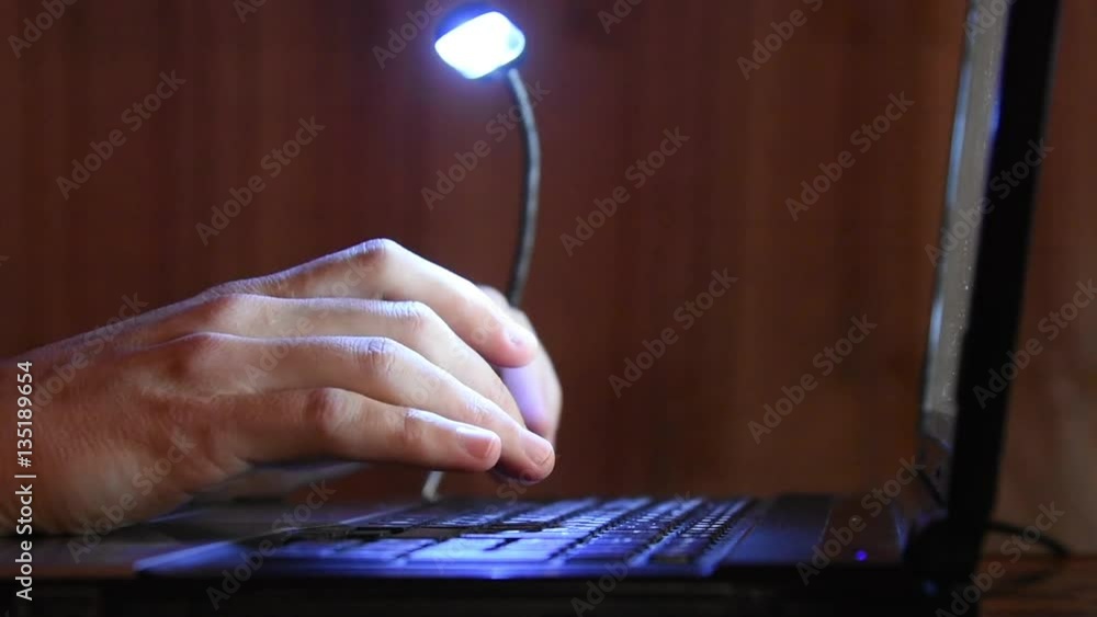 Hand typing on the computer keyboard, the keyboard is illuminated from ...