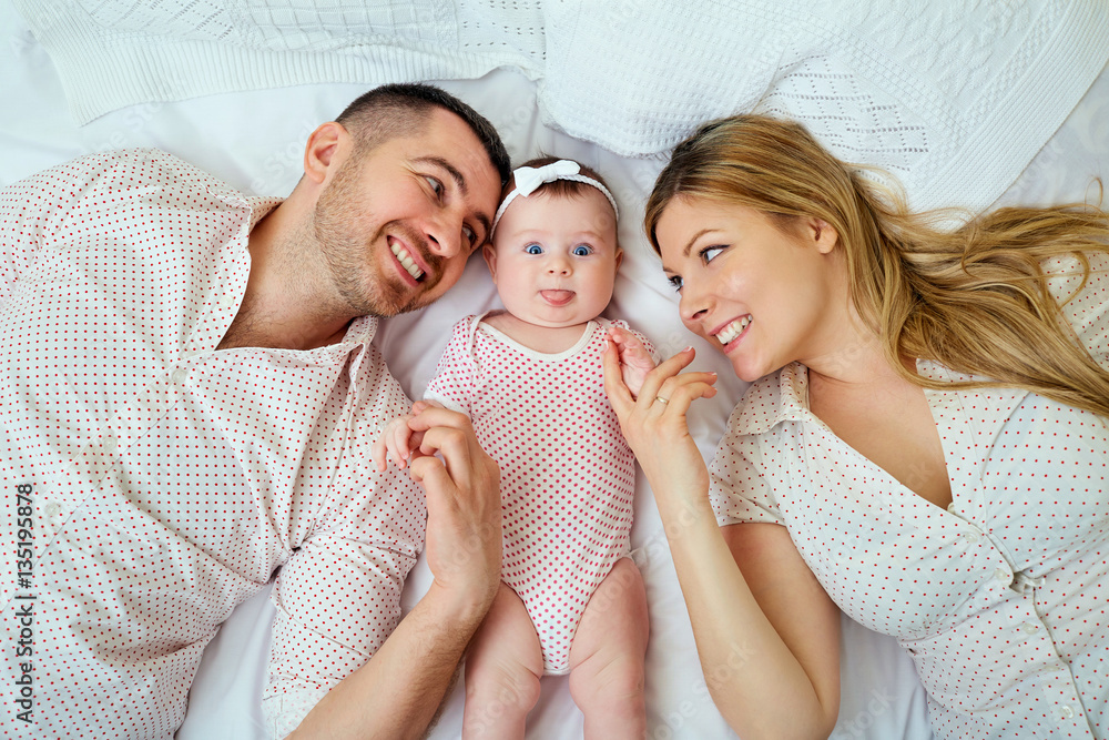 Mother and father happy smiling with her baby lying the bed. Parents ...