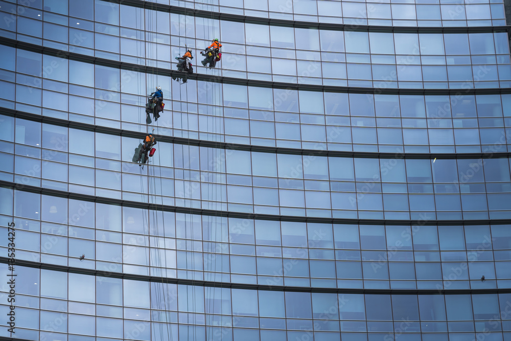 Window washers cleaning the glass facade of a skyscraper, high risk ...