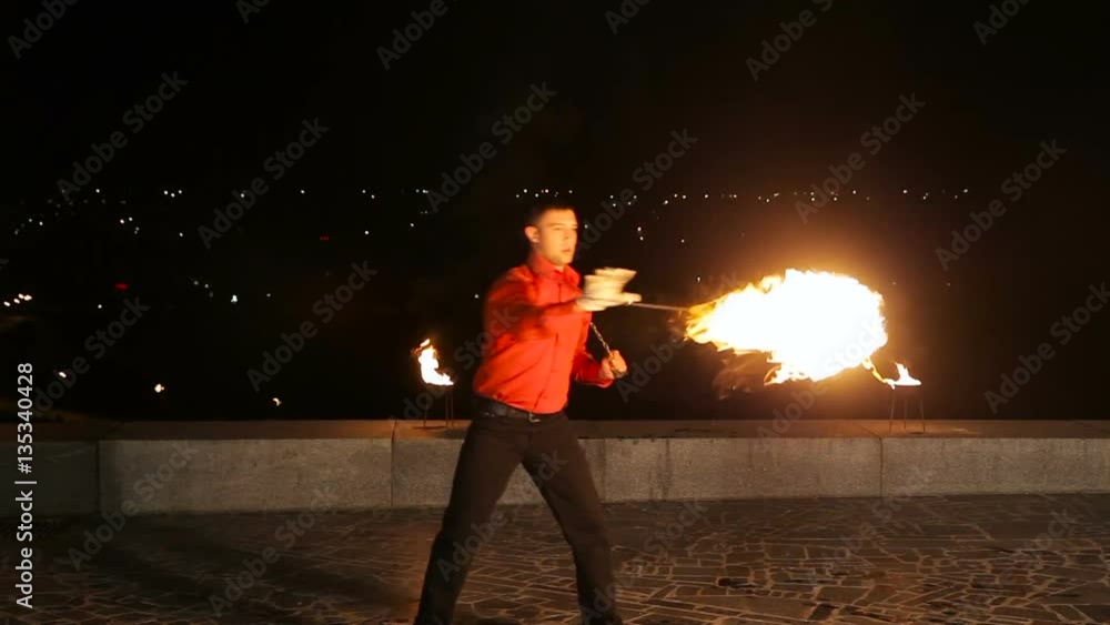 Artist man rotates the fireball.Man twist fiery circles on a fire show ...