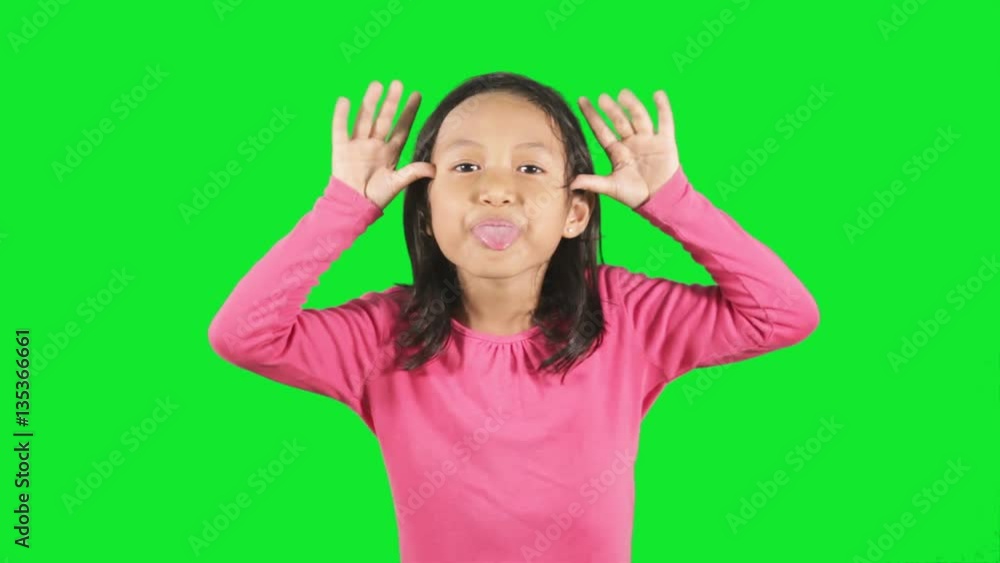Funny little girl showing a silly face expression in the studio with ...
