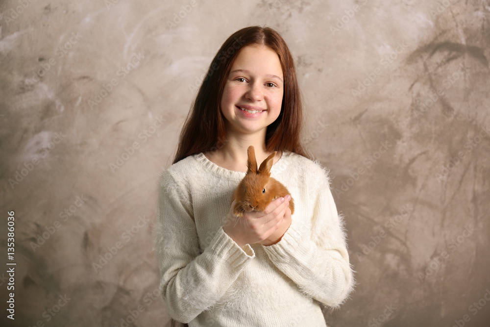 Cute girl holding rabbit on grey wall background Stock Photo | Adobe Stock