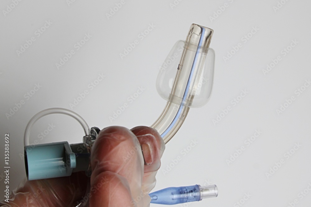 Tracheostomy tube held in left hand in glove, inflated polyurethane ...