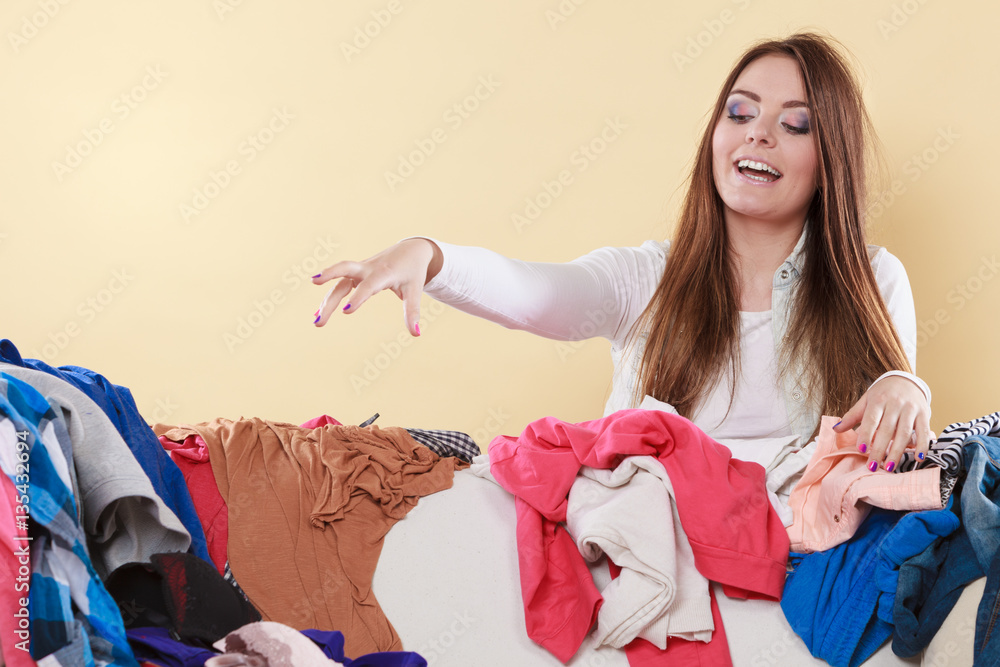 Happy woman picking clothes up in messy room. Stock Photo | Adobe Stock