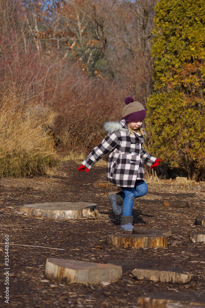 adorable school age girl jumping on log stumps Stock-Foto | Adobe Stock