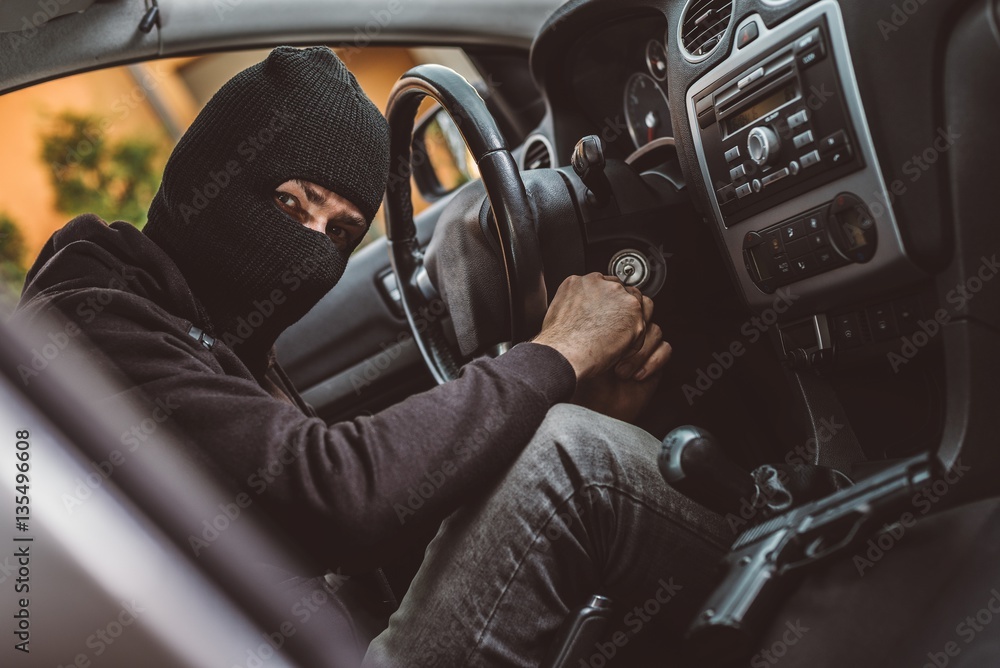 Foto de Auto thief trying to start car with screwdriver in ignition do Stock | Adobe Stock