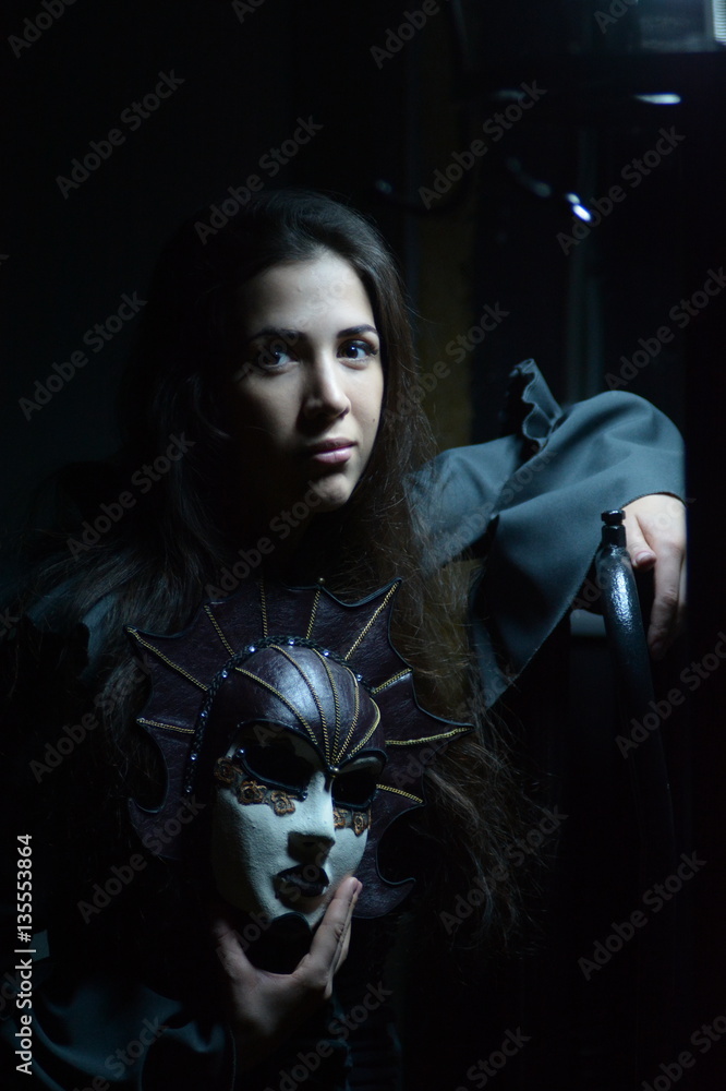 young brunette woman holding a theater mask on a dark background Stock ...