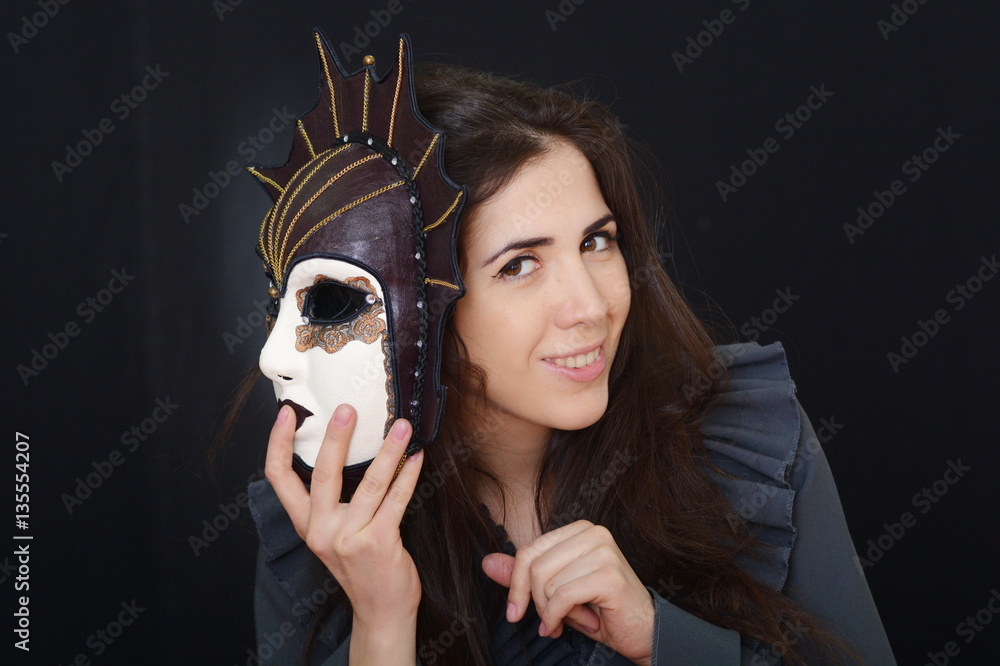 young brunette woman holding a theater mask on a dark background Stock ...