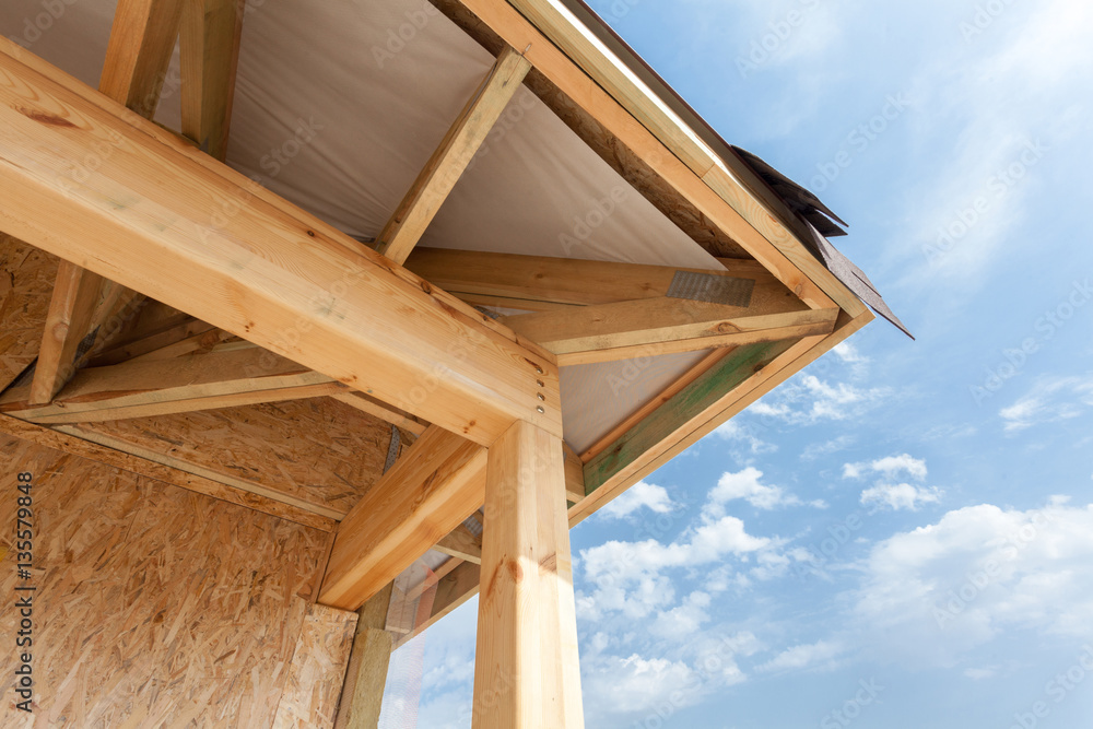 Corner of house with eaves, wooden beams and roof asphalt shingles ...